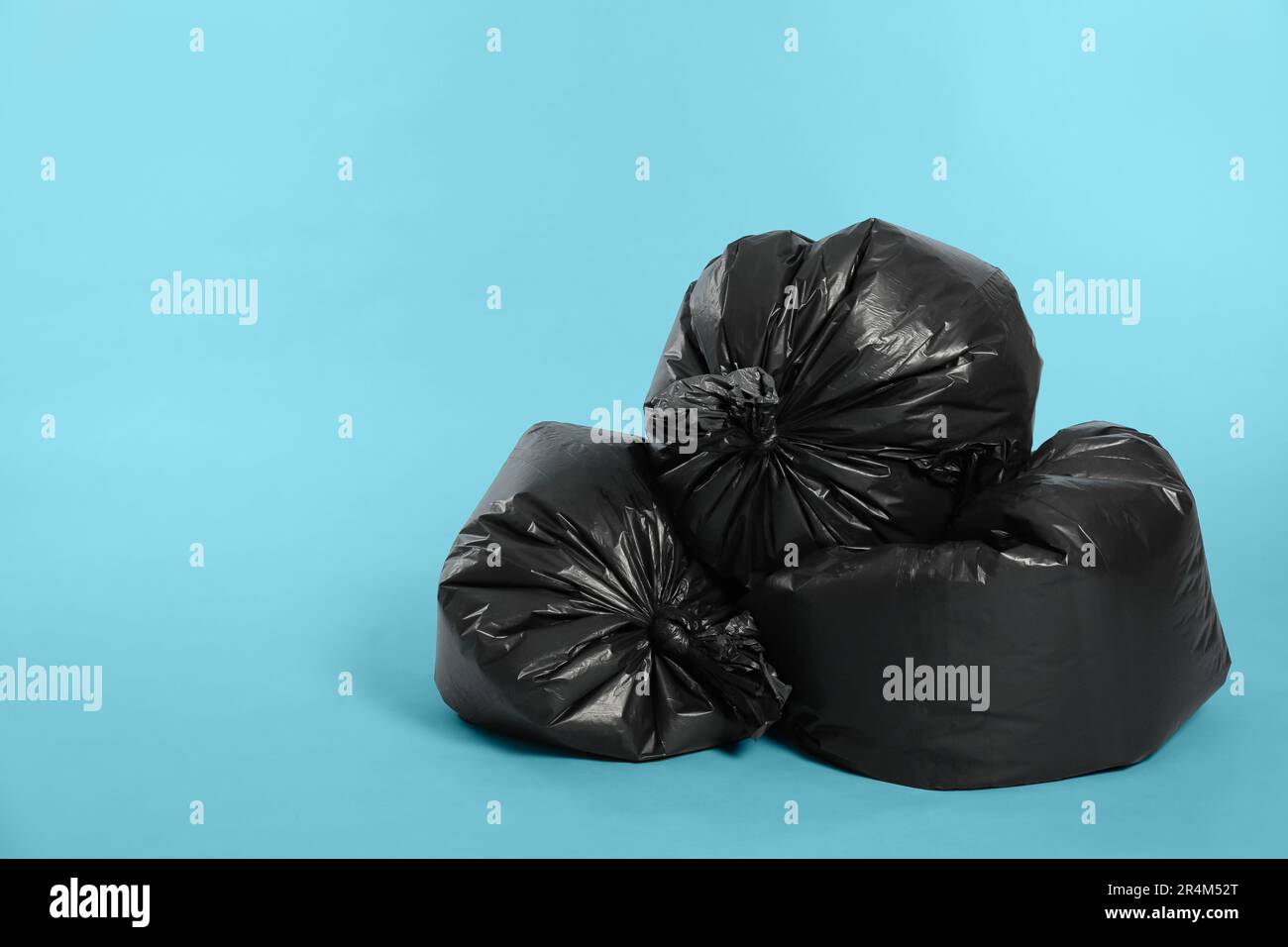 Trash bags full of garbage on light blue background. Space for text ...