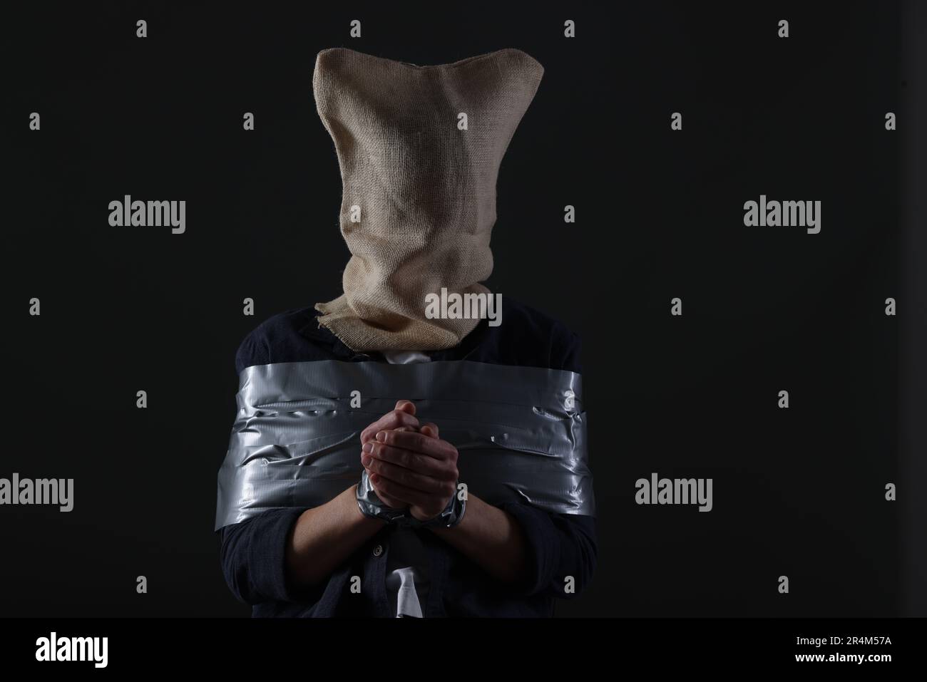 Taped up woman with bag on her head on dark background. Hostage Stock ...