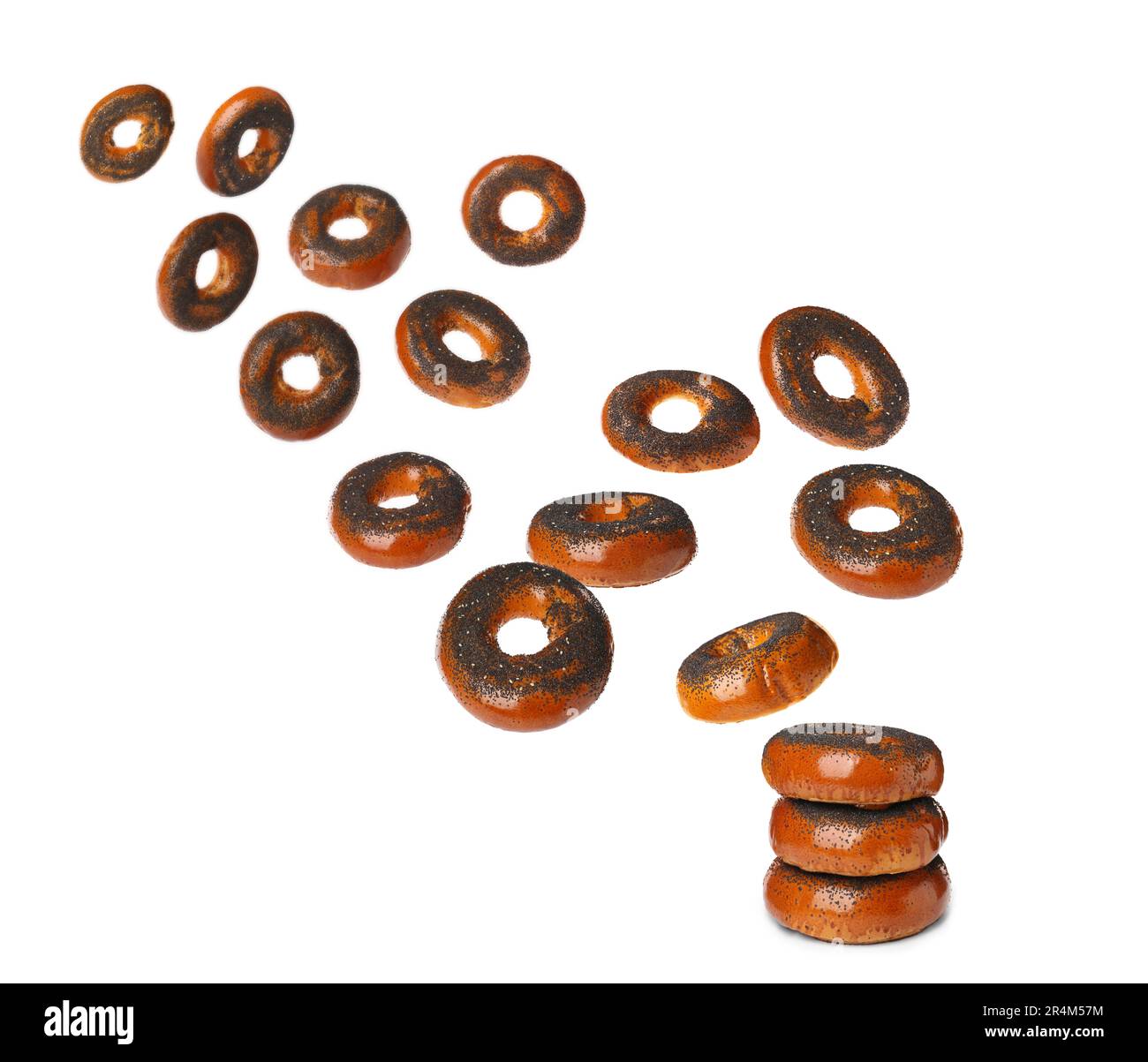 Many fresh bagels with poppy seeds falling onto stack on white ...