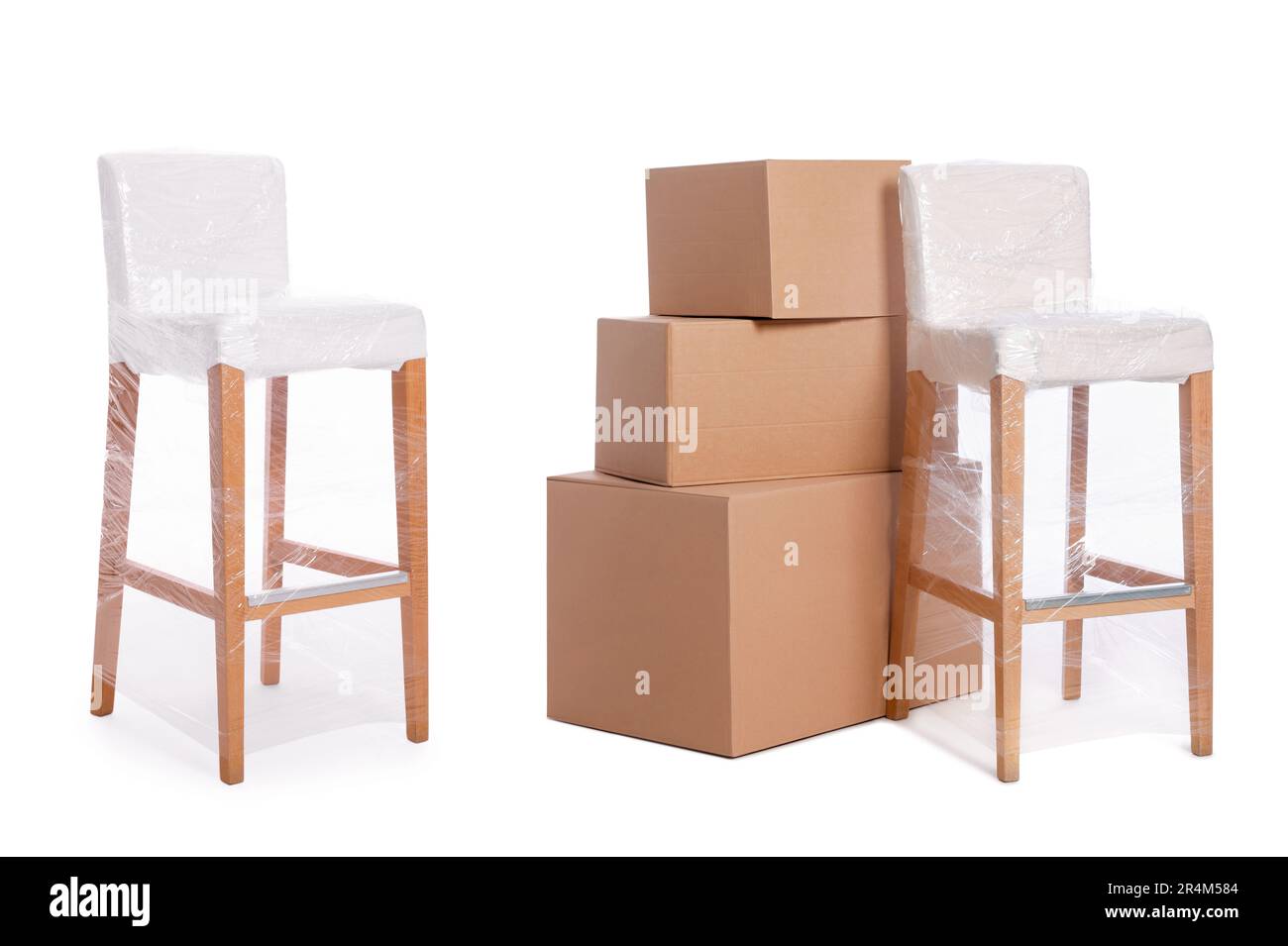 Chairs wrapped with stretch film and cardboard boxes on white ...