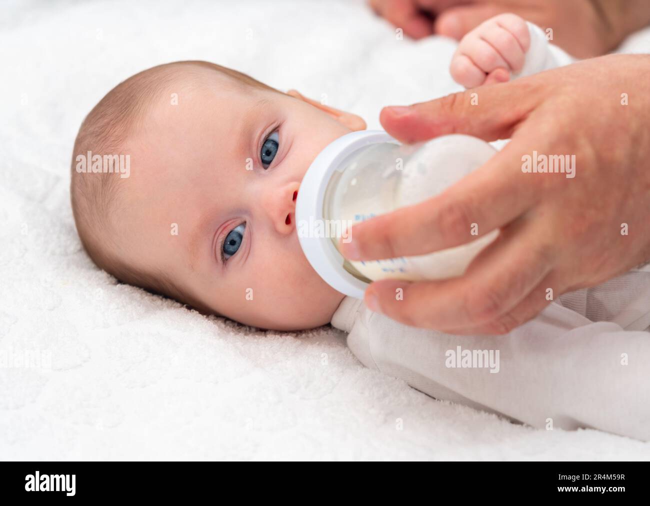 Baby girl eating formula from a bottle supported by her father Stock ...