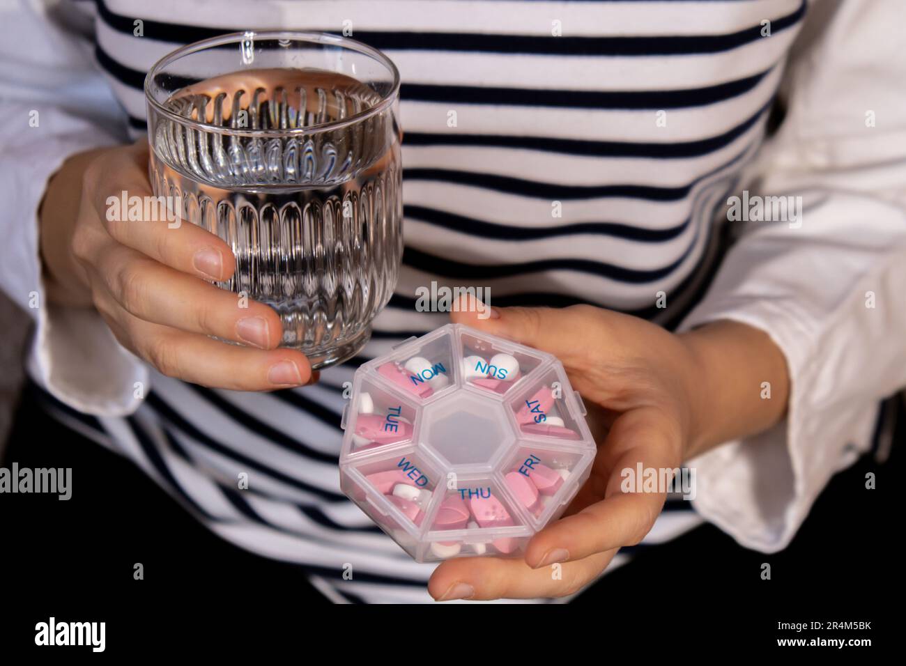 Female hands sorting pills Organizer weekly shots Glass of water ...