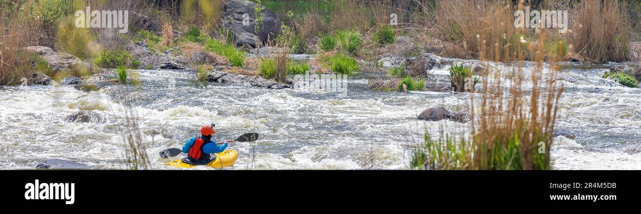A water sportsman on a canoe overcomes a turbulent stream of water on ...