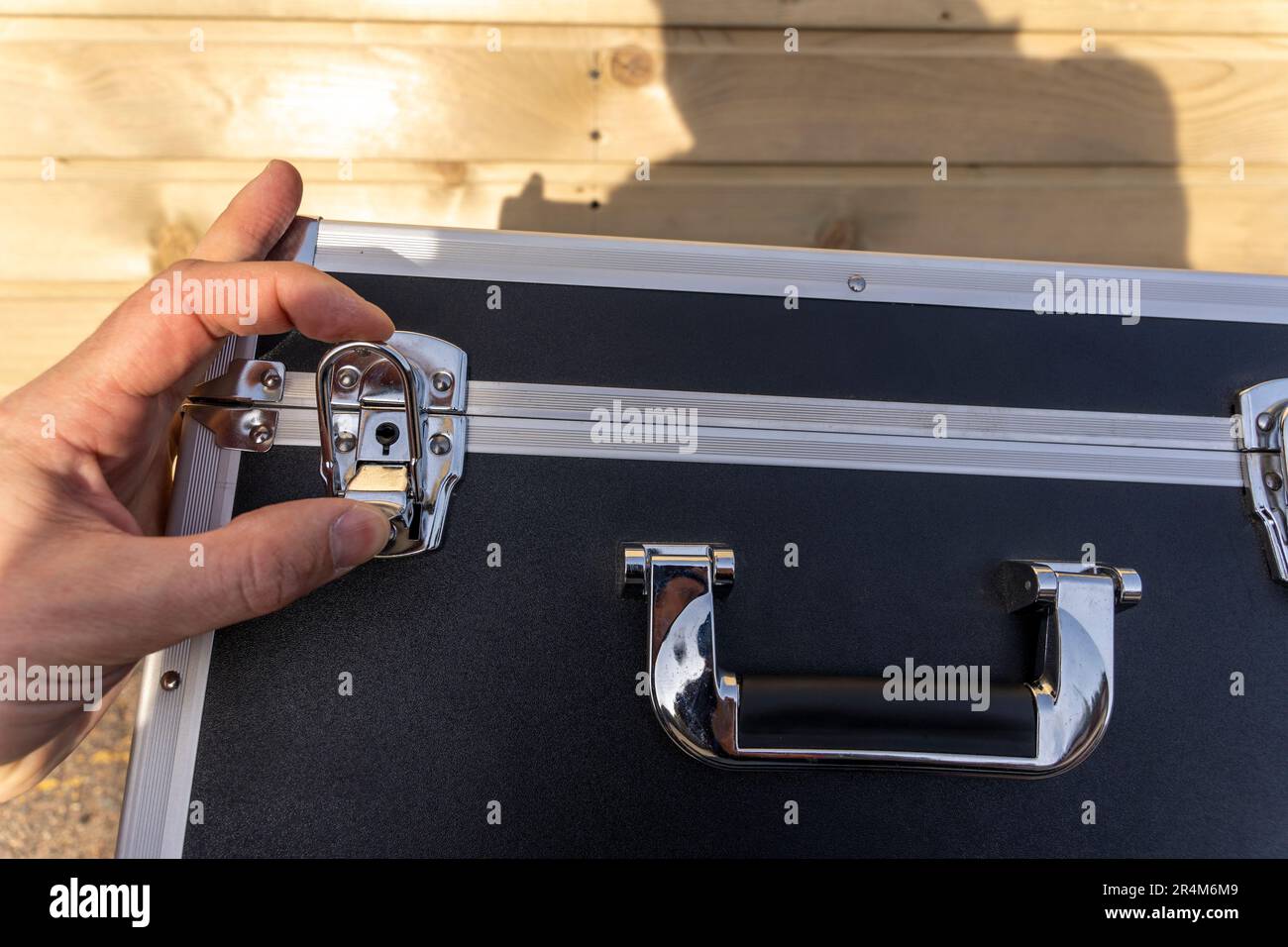 person 's hand opens the latches and locks of a special rigid suitcase ...
