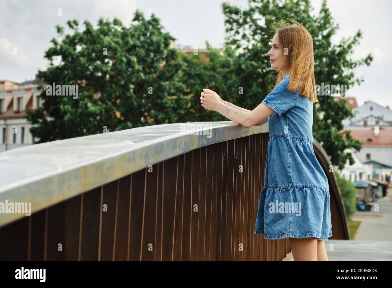 Woman leaning on a railing and surveys neighbourhood from height of ...