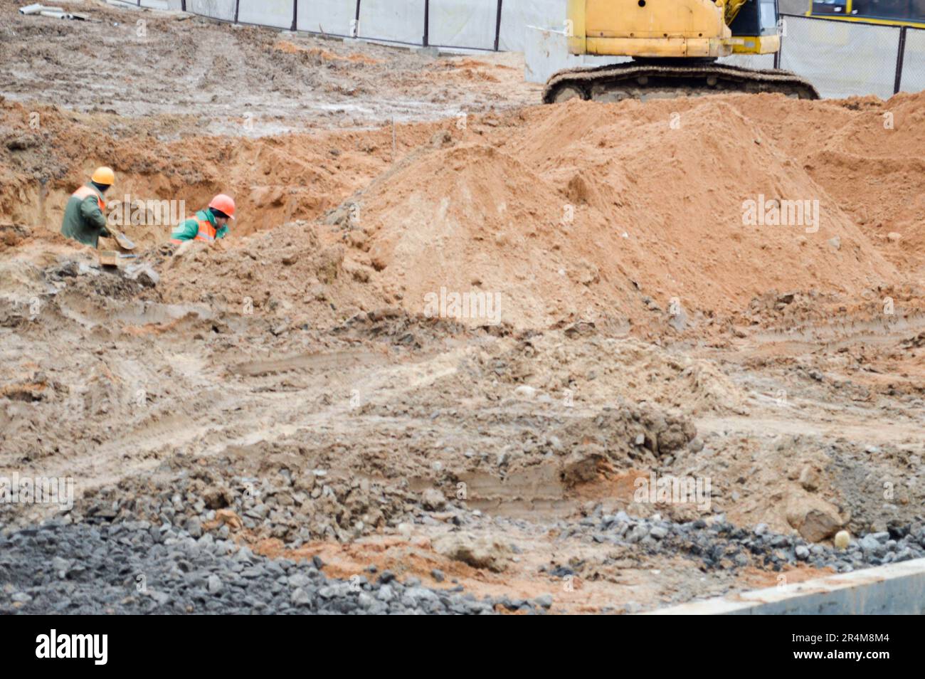 Builders workers men in helmets and robes work, dig a hole in the ...