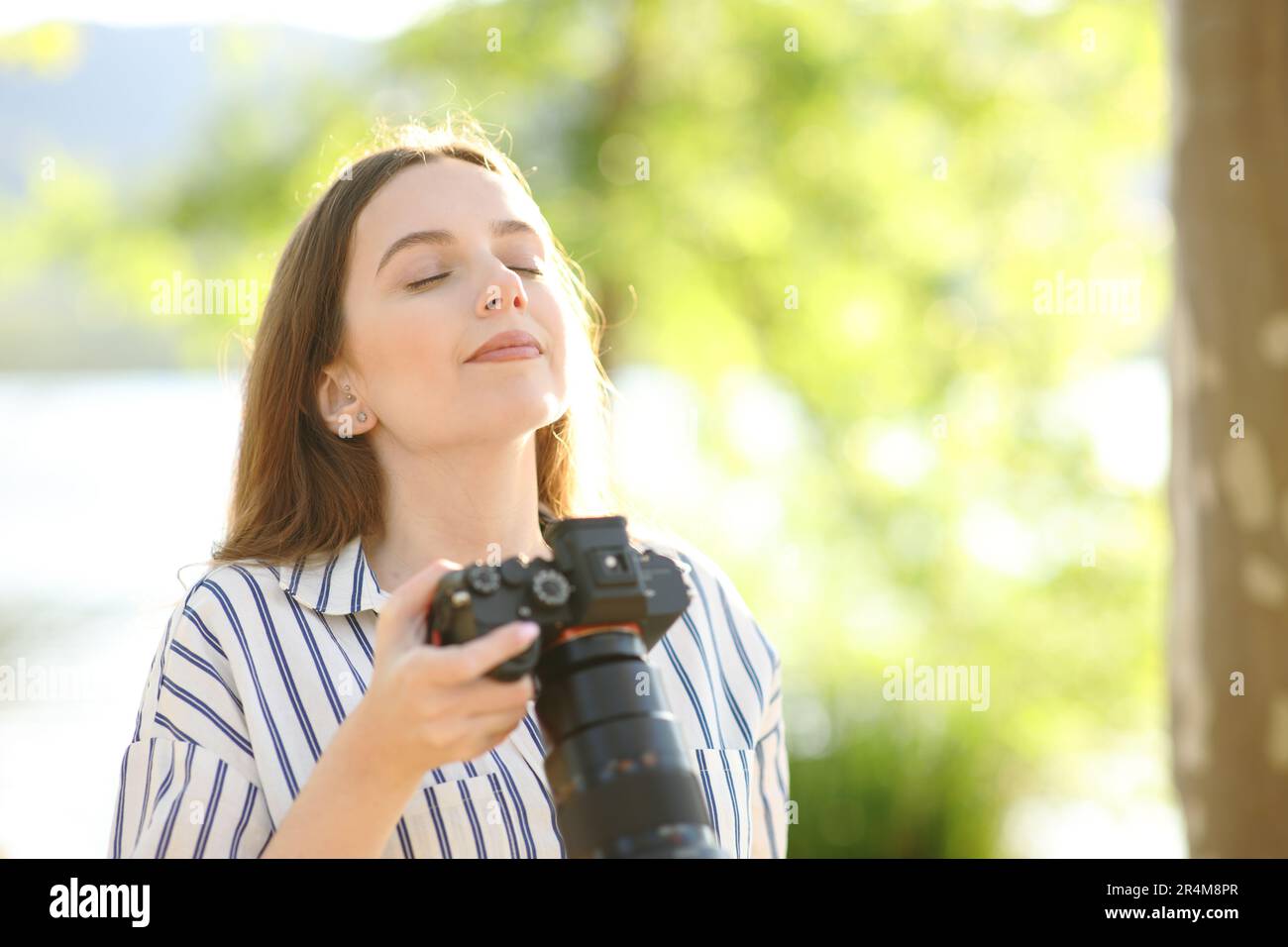Photographer breathing fresh air holding mirrorless camera in nature ...