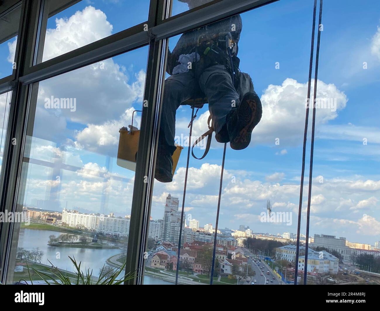 A male window washer worker, industrial climber hangs from a tall ...