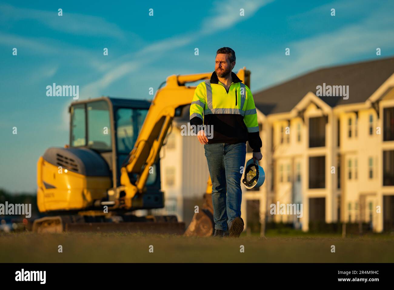Builder in a construction site. Builder with excavator ready to build ...