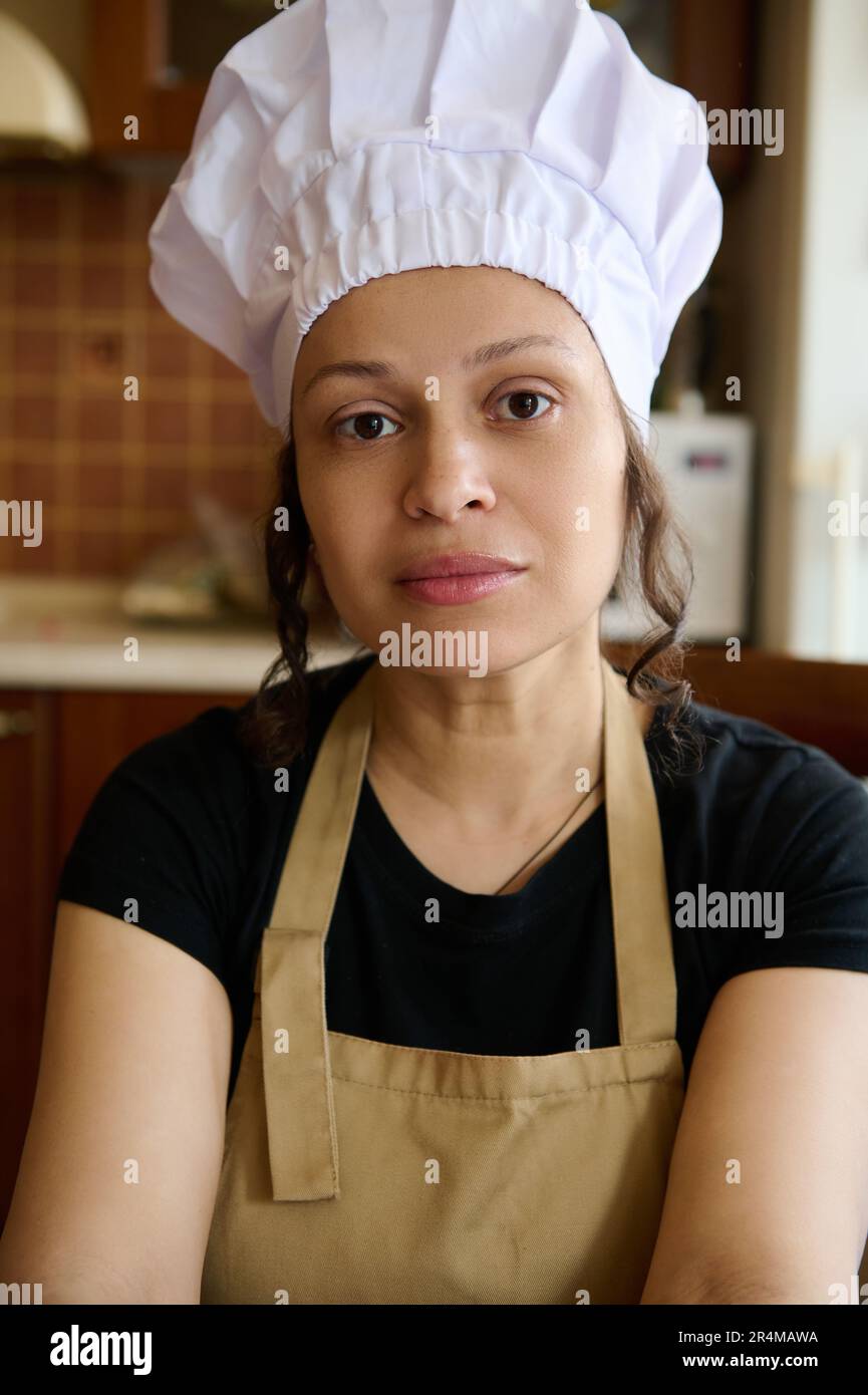 Confident portrait of a beautiful female baker confectioner, wearing ...