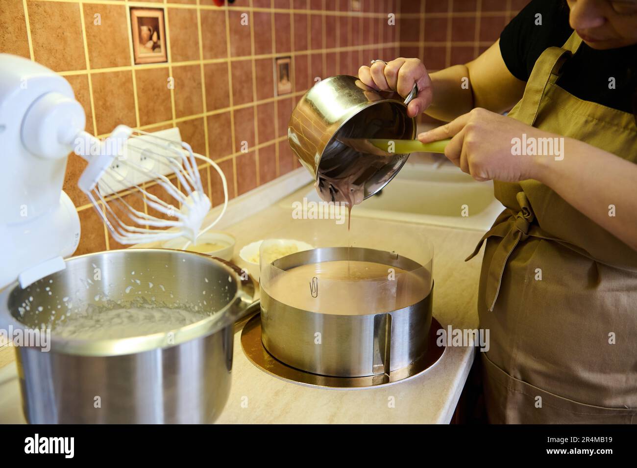 Close-up Pouring a chocolate mass into a detachable cake mold for ...