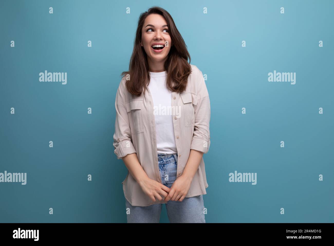 pretty 25 year old woman in a casual look smiles cutely on a blue ...