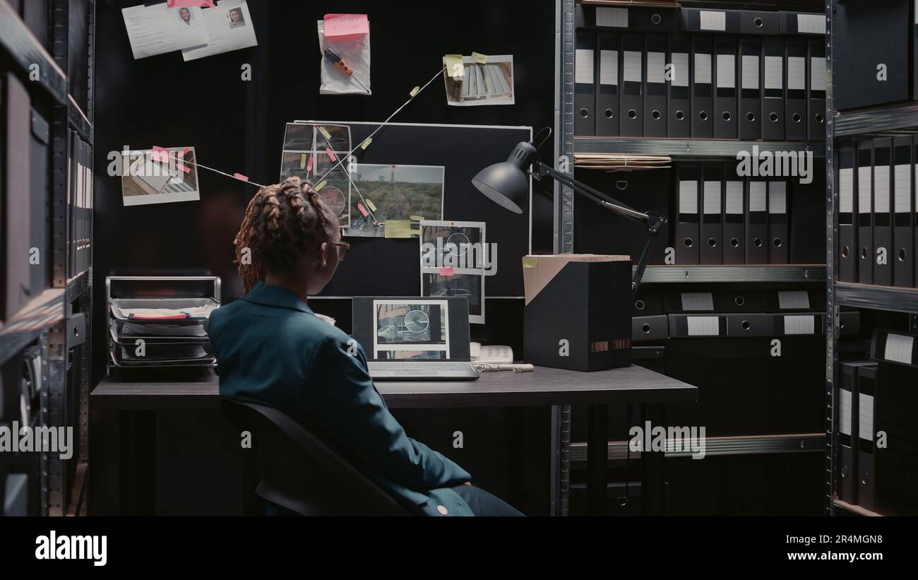 African american police investigator reading case file Stock Photo - Alamy
