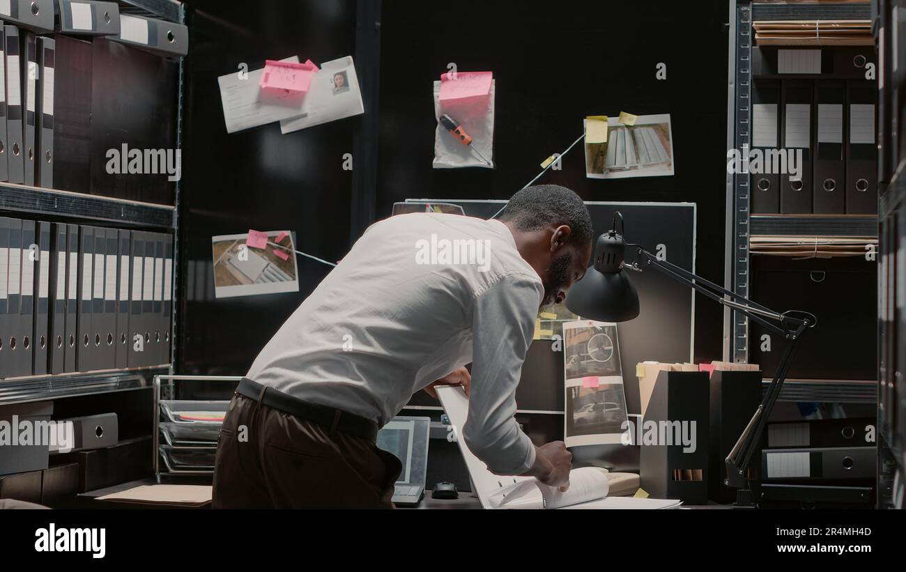 Male inspector examining forensic evidence on map Stock Photo - Alamy