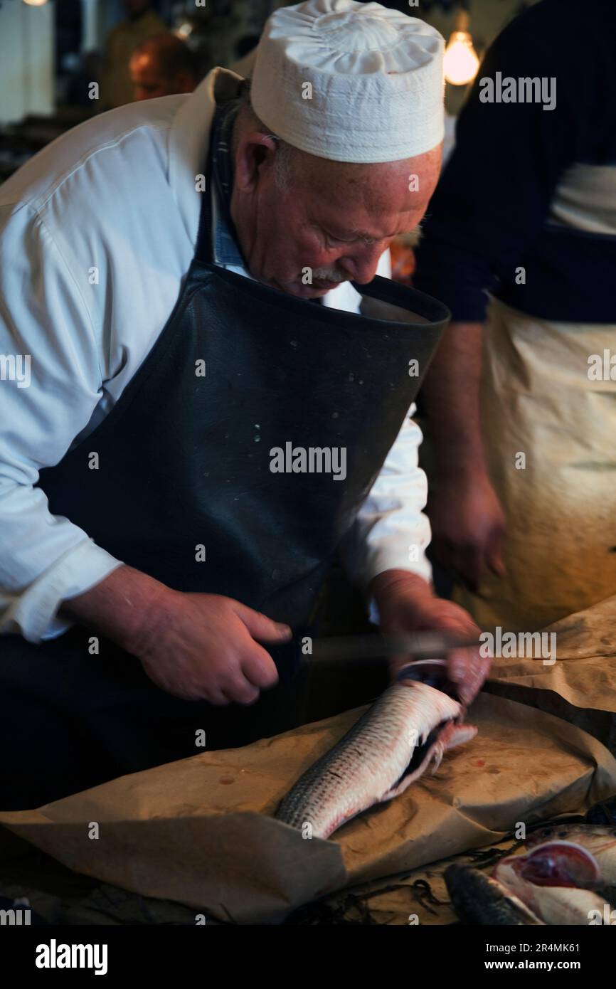 A fishmonger filleting fish in a market in the Mediterranean town of ...