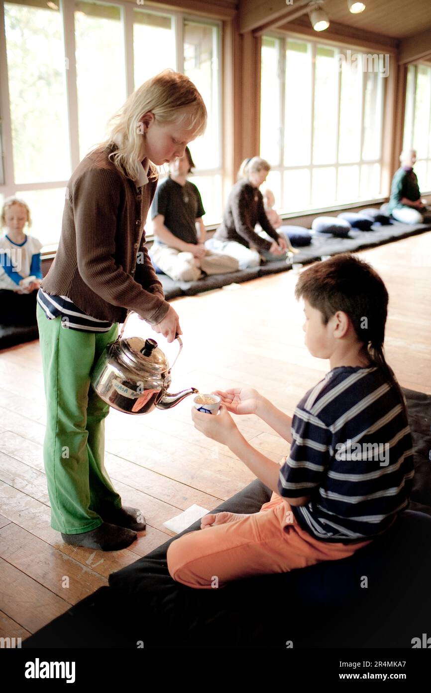 A young girl serves tea at an alter during a Buddhist family retreat on ...