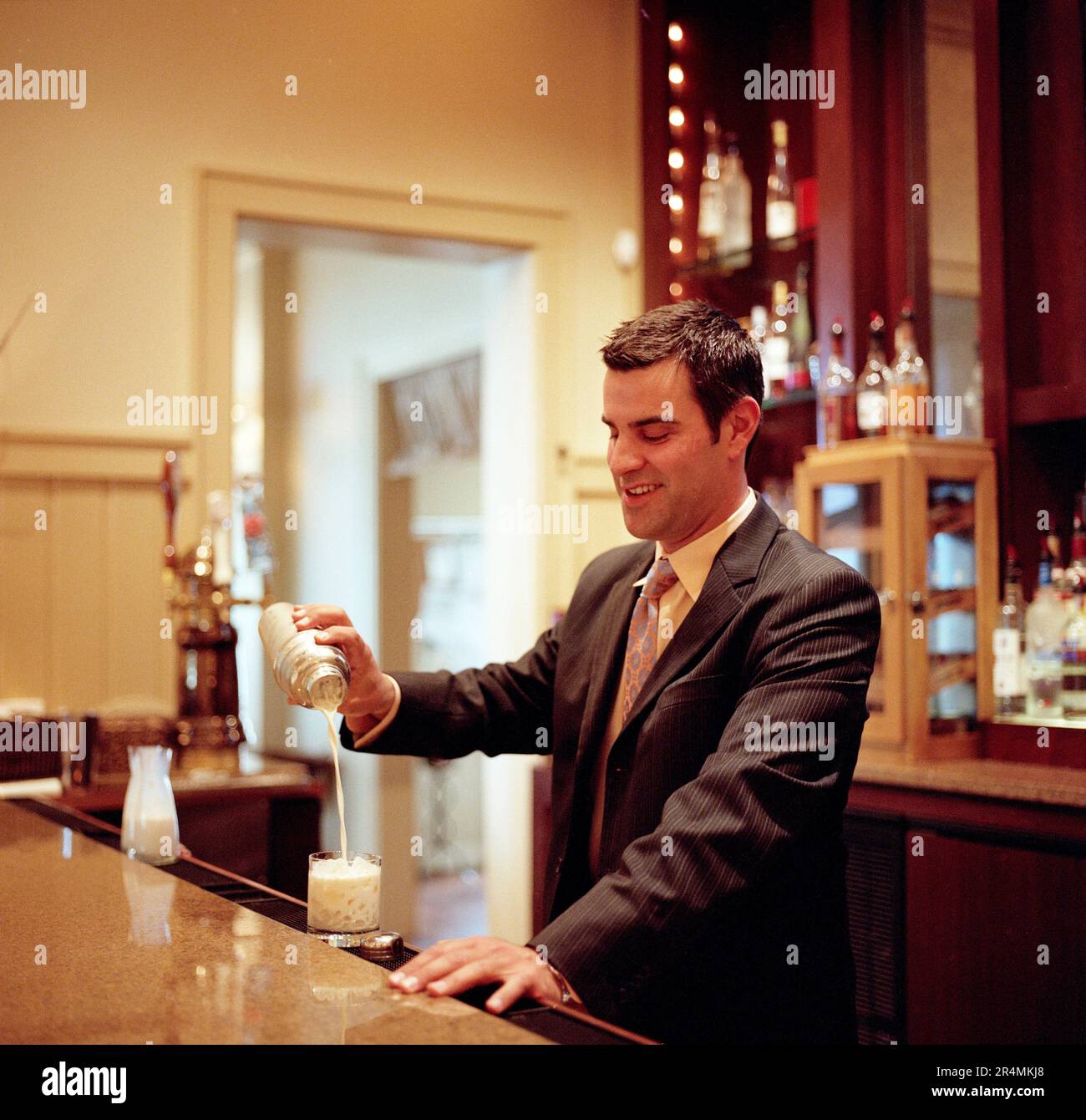 A portrait of a man pouring a cocktail behind the bar Stock Photo - Alamy