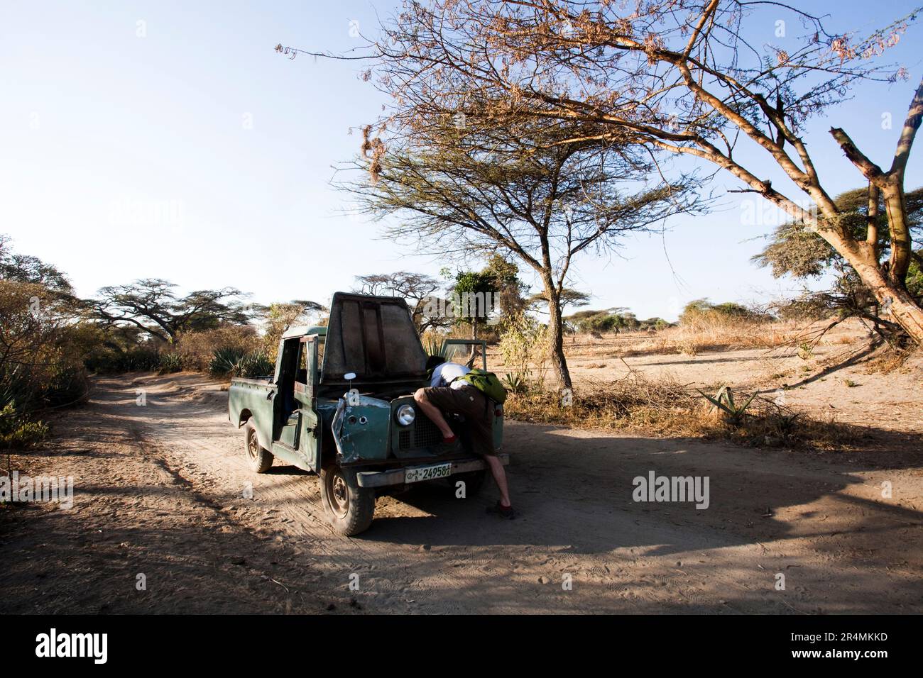 A man looks inside a beat up old car after it breaks down in a rural ...