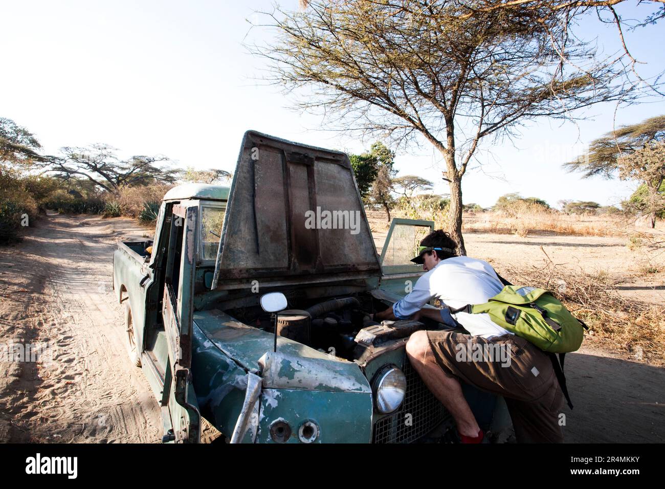 A man looks inside a beat up old car after it breaks down in a rural ...