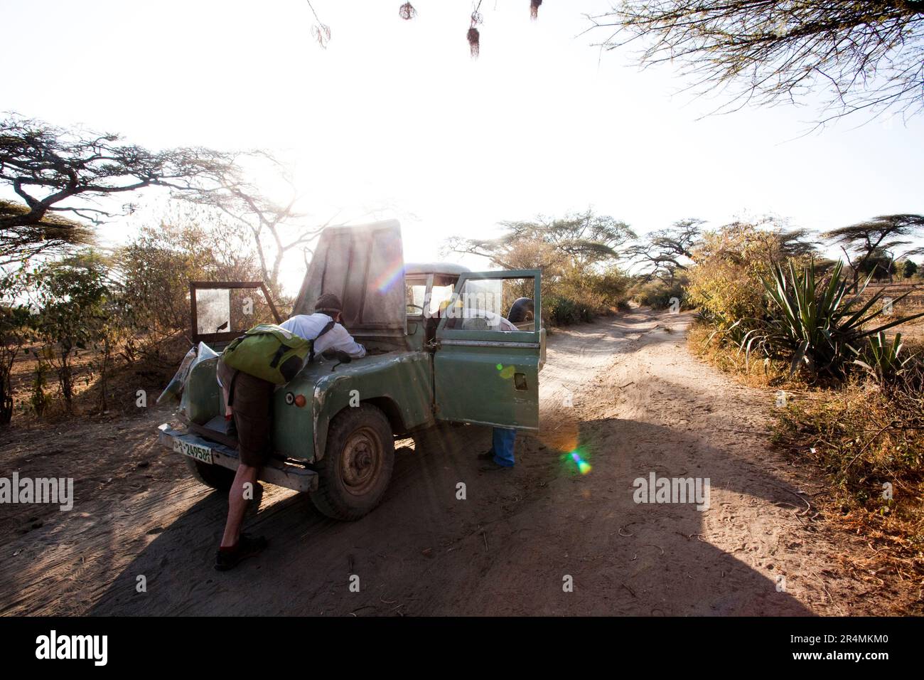 A man looks inside a beat up old car after it breaks down in a rural ...