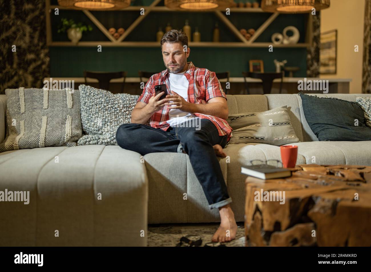 Handsome man with mobile phone sitting at home. American man using ...