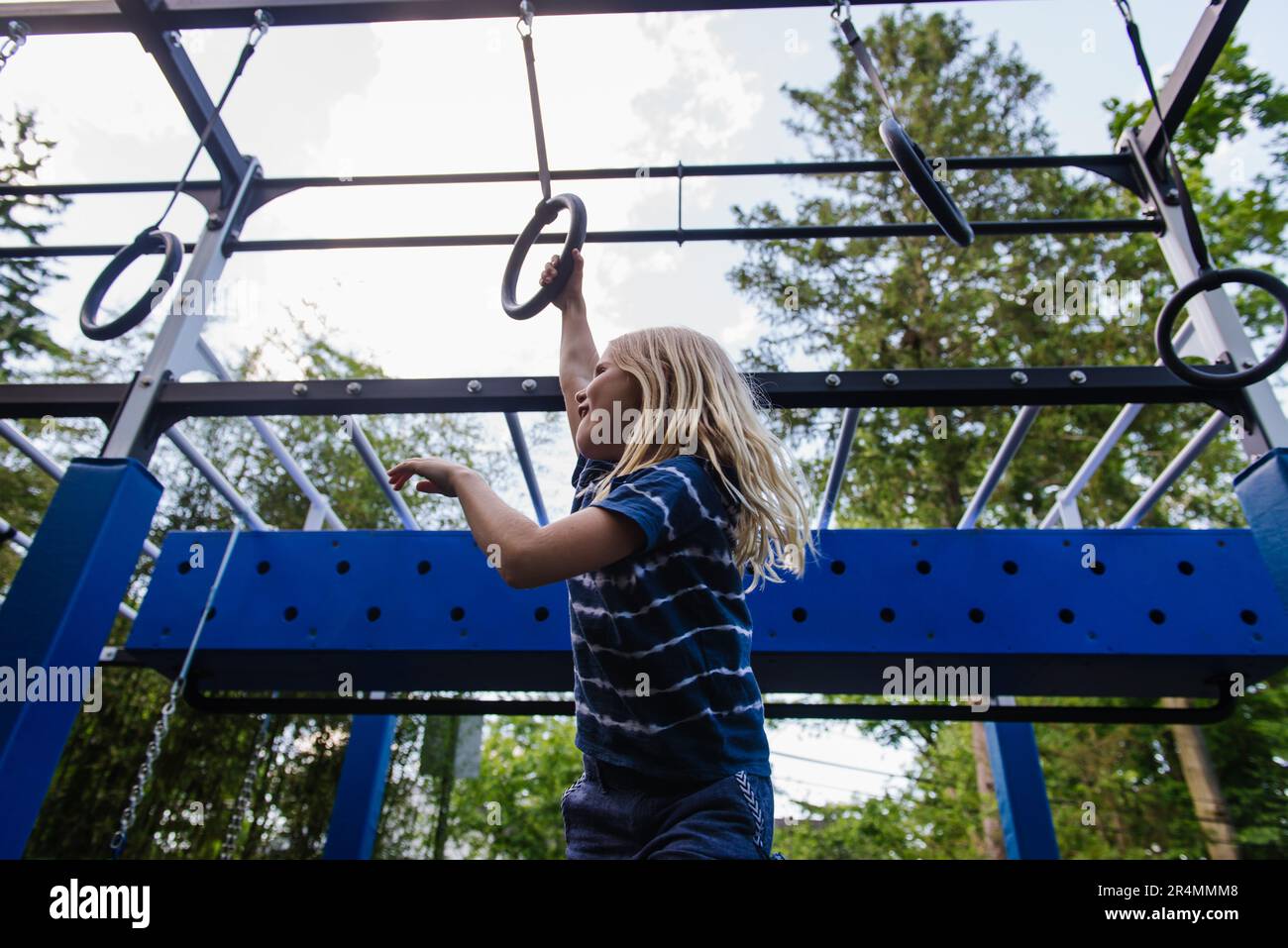 Girl swinging on rings on playground Stock Photo - Alamy