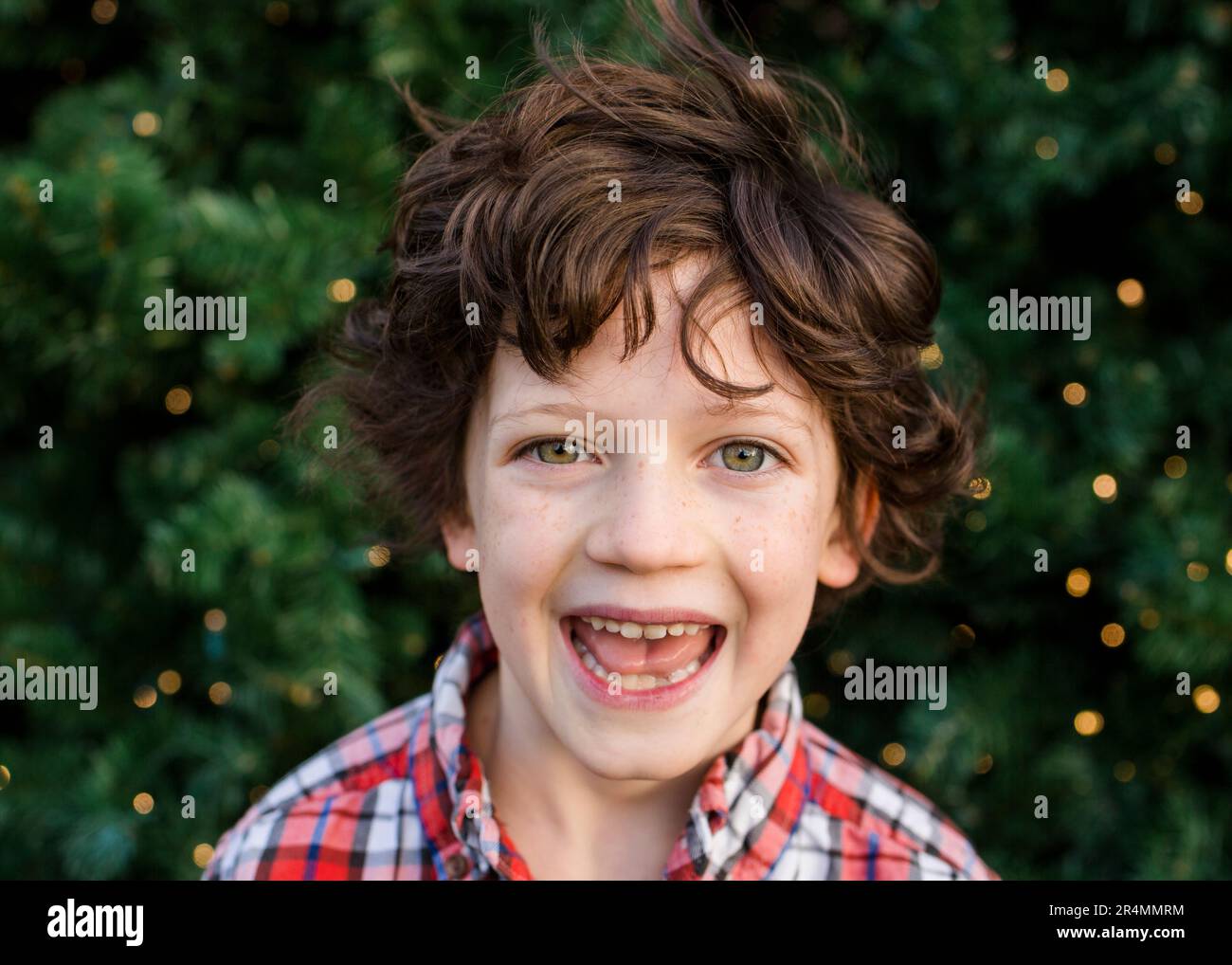 head shot of a laughing happy child standing in front of lit tree Stock ...