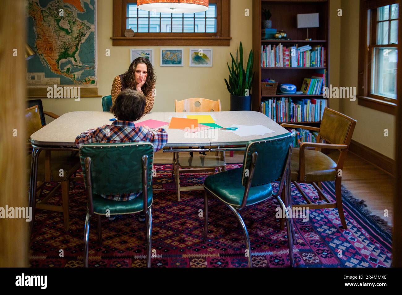 A Mom and child sit at a dining room table doing homework together ...