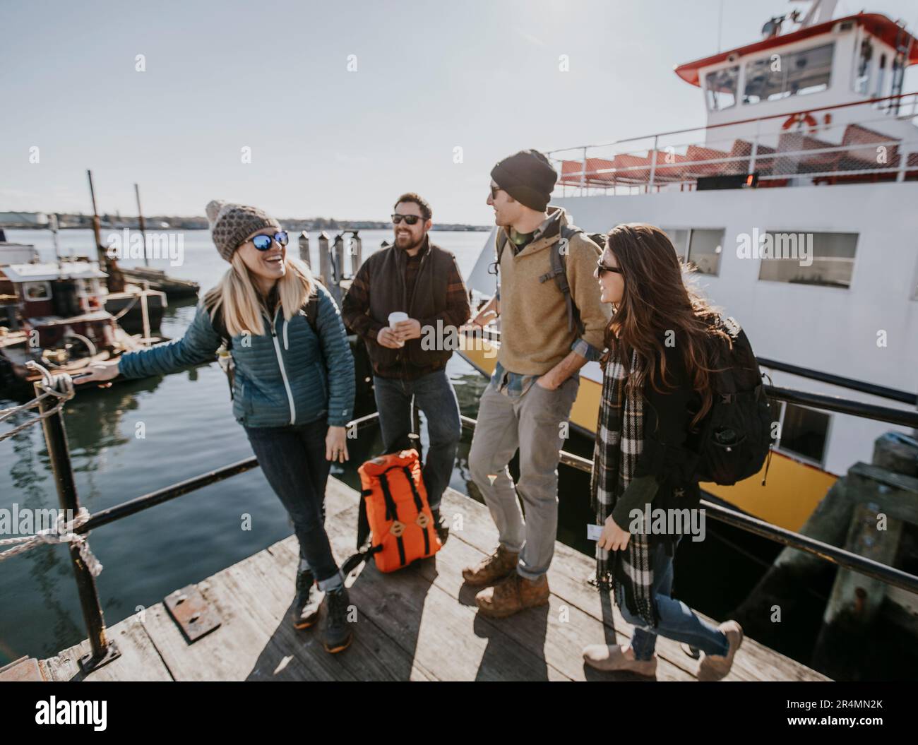 Four young adult friends wait on the waterfront in Portland, Maine ...