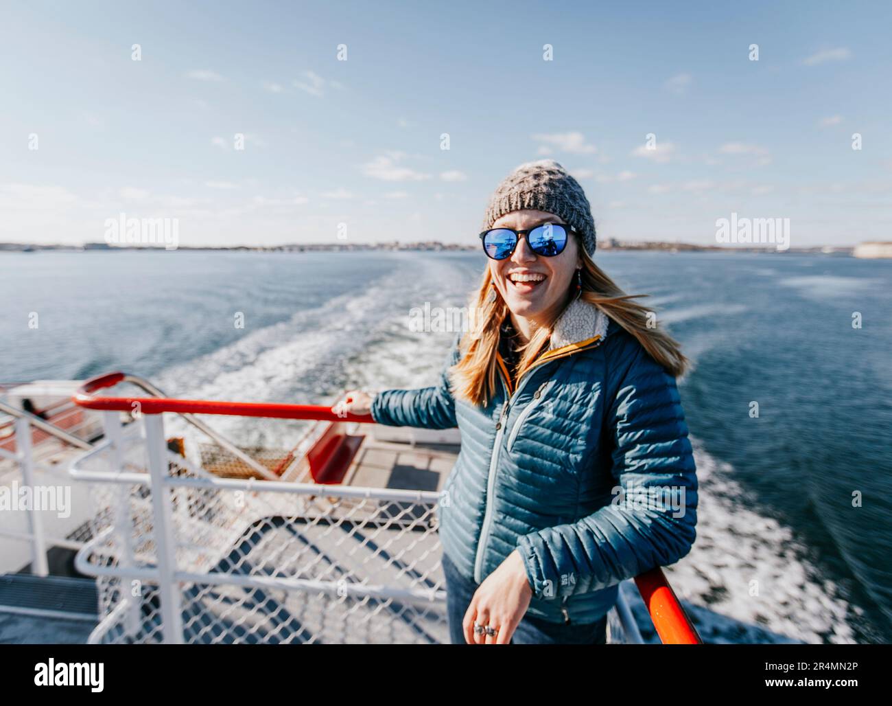 A young woman in a hat smiles while riding a ferry in Portland Maine ...