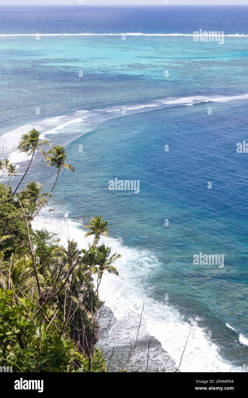 Aerial view of waves breaking on reef and tropical palm trees, Samoa ...