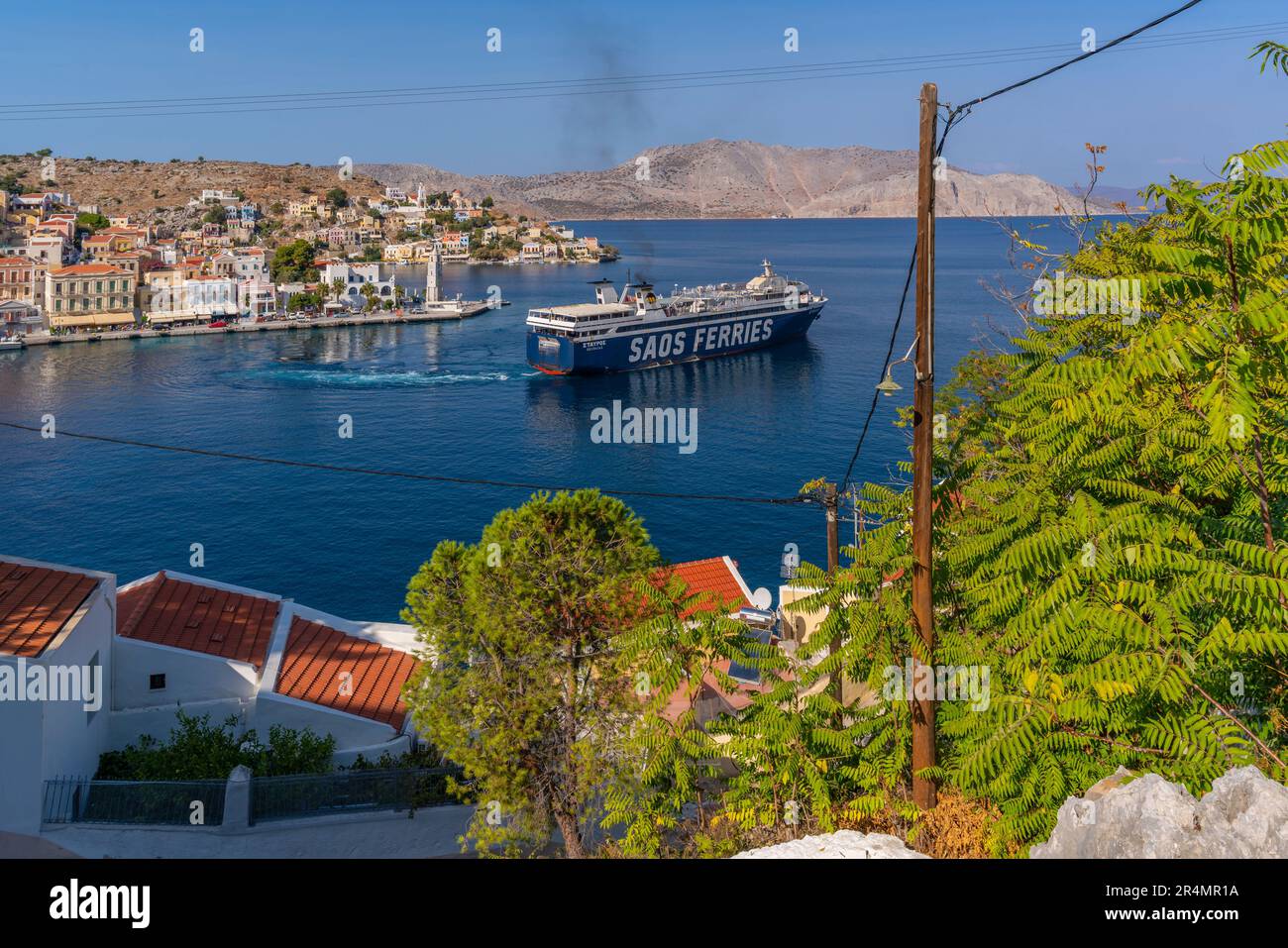 View of ferry boat leaving harbour from elevated position in Symi Town ...