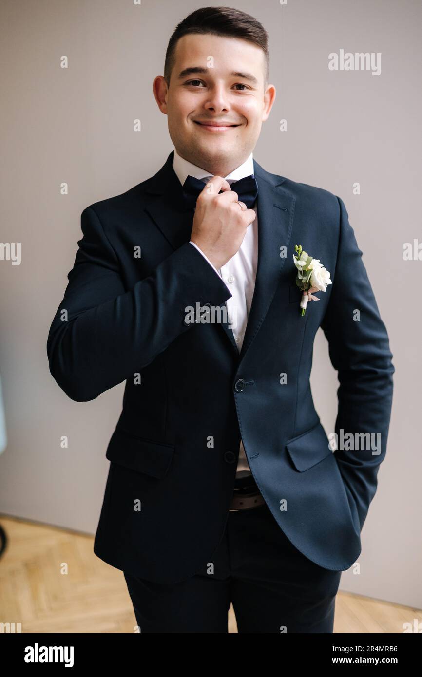 Portrait of handsome groom in dark blue suit preparing for first view ...