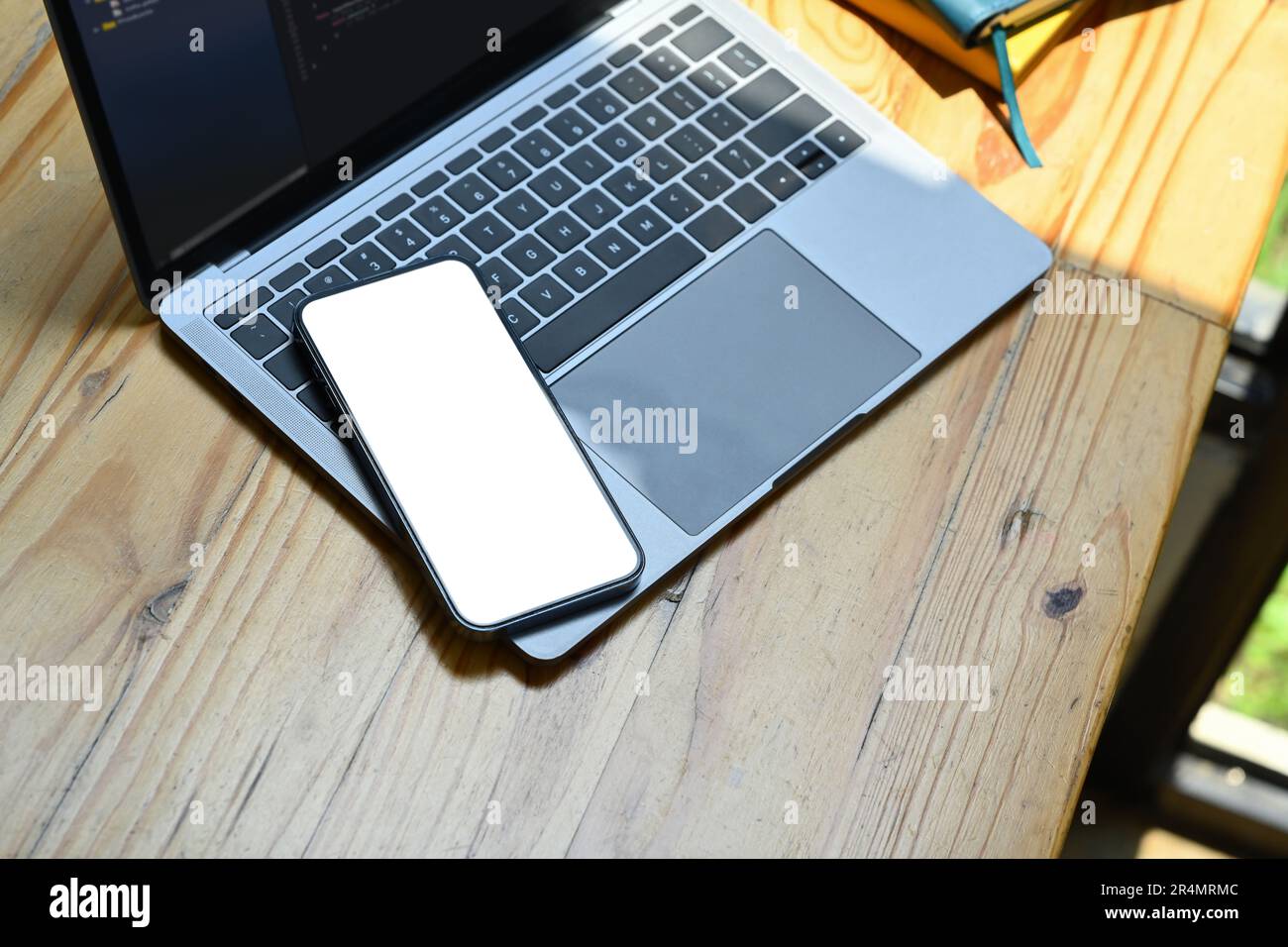 Smartphone with white blank screen and laptop computer on wooden office ...