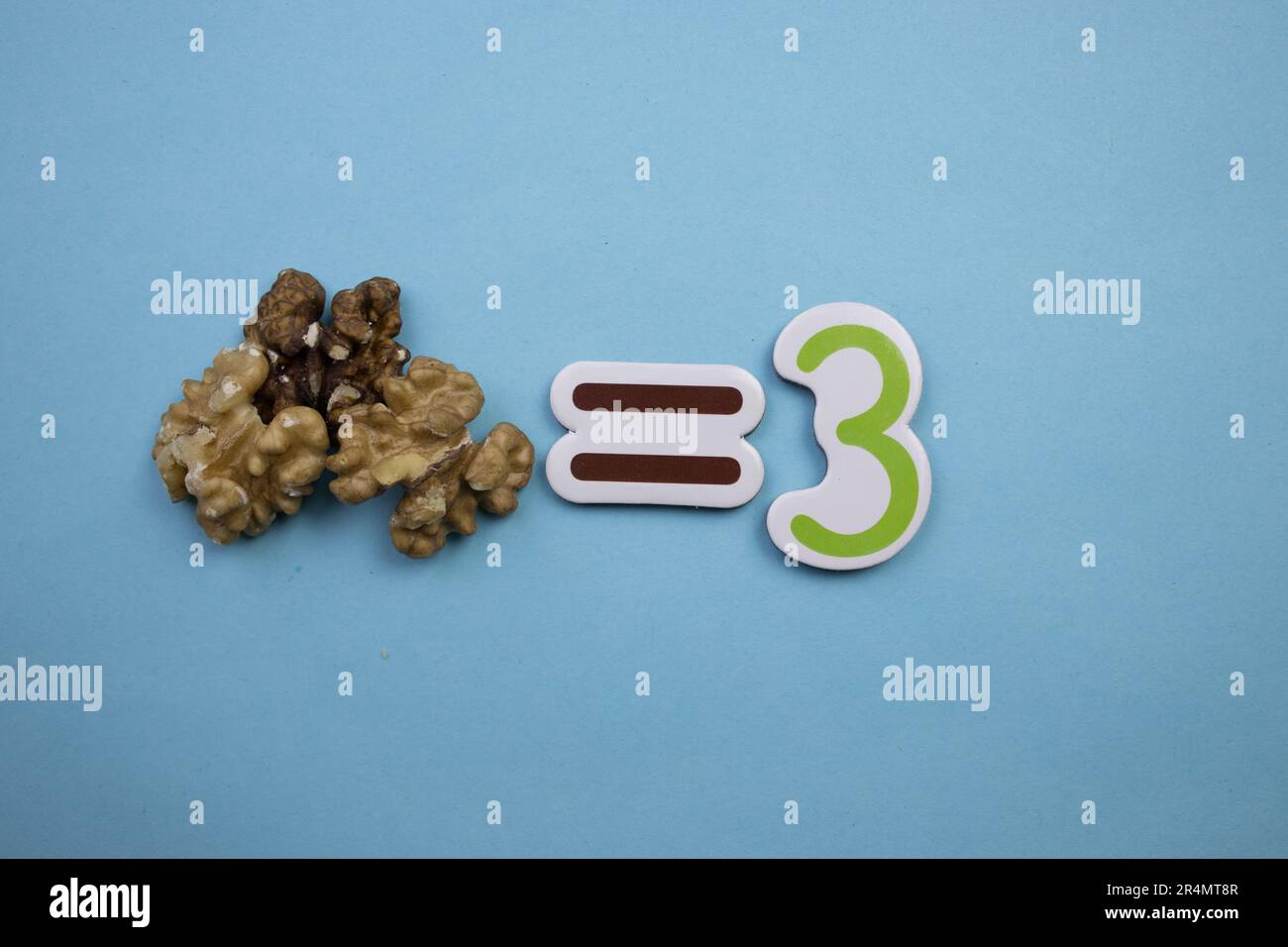 Three walnut kernels, photographed from above, placed on a blue ...