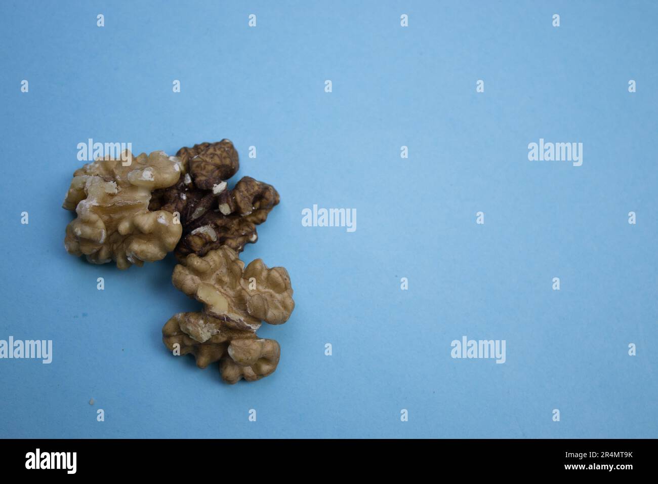 Three walnut kernels placed on the edge of a blue background ...