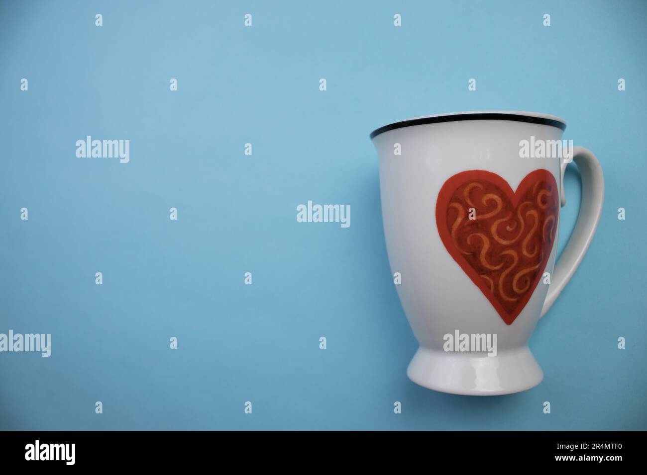 White mug with heart, photographed from above, placed on the edge of a ...