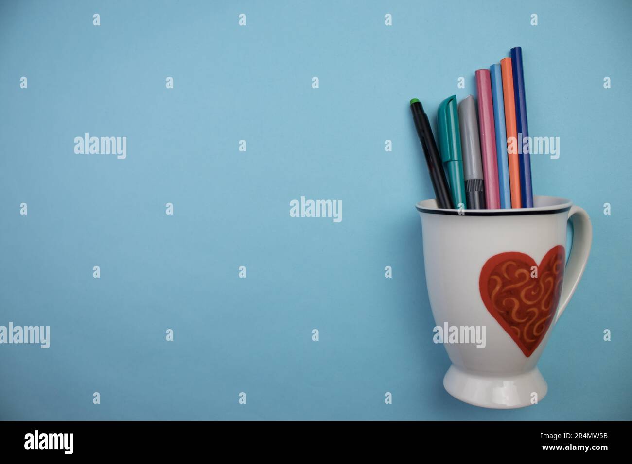 Heart-shaped mug photographed from above, placed on the edge of a blue ...