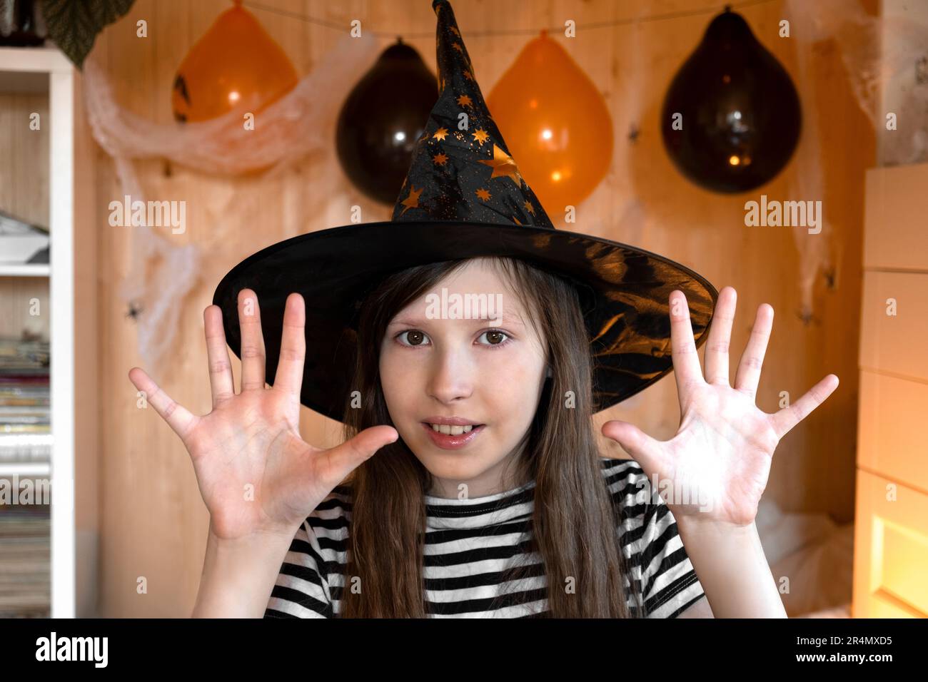 Little pretty girl witch in black wizard hat says Boo with scary ...