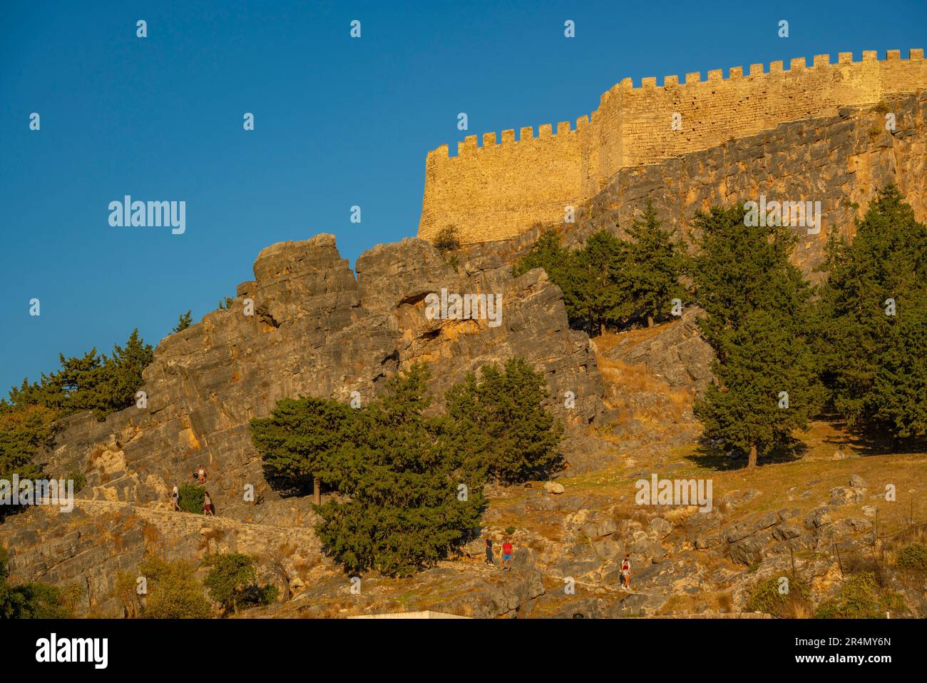 View of Lindos Acropolis from street in town at sunset, Lindos, Rhodes ...