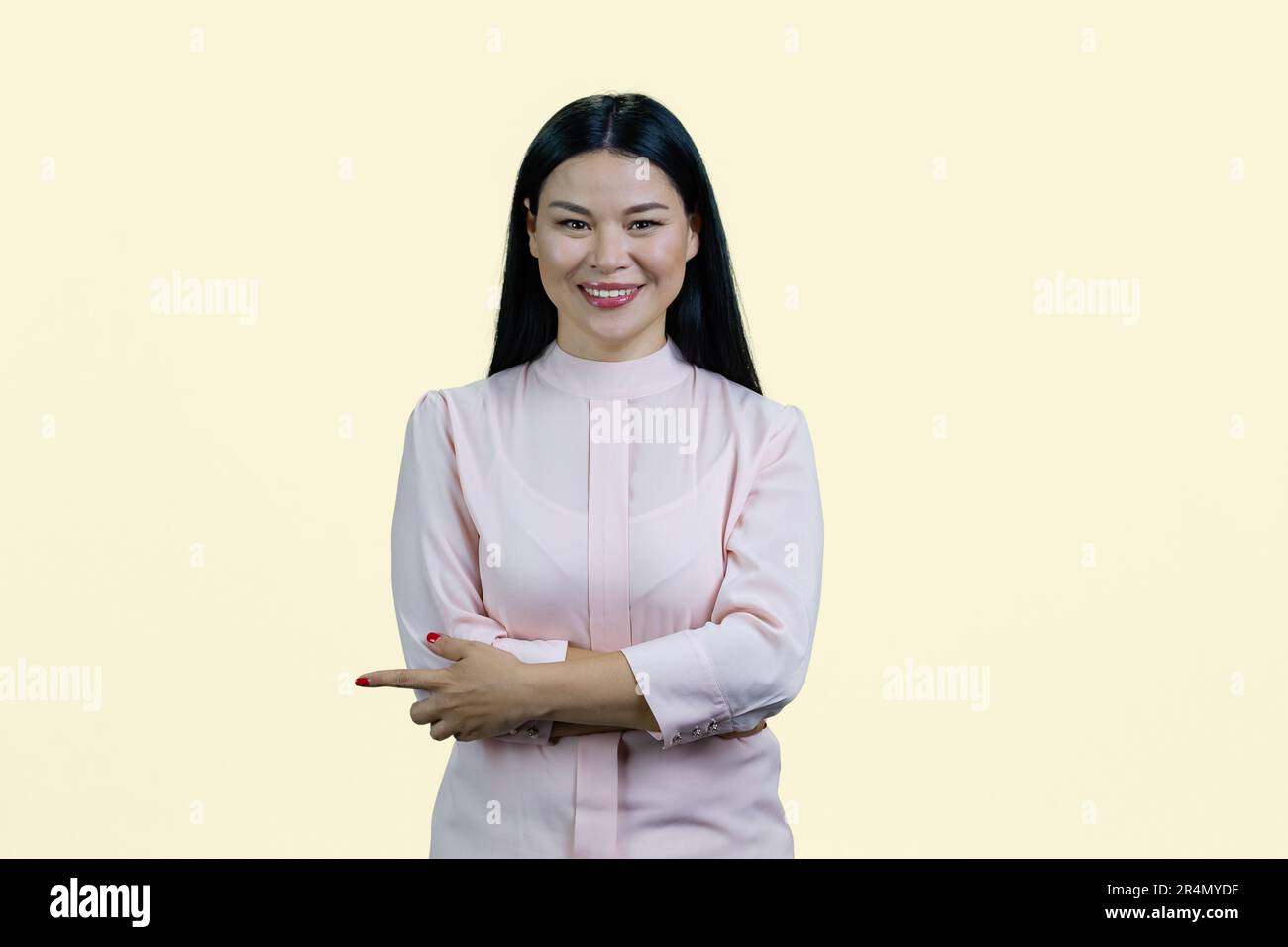 Portrait of happy cheerful asian woman with folded arms pointing to the ...