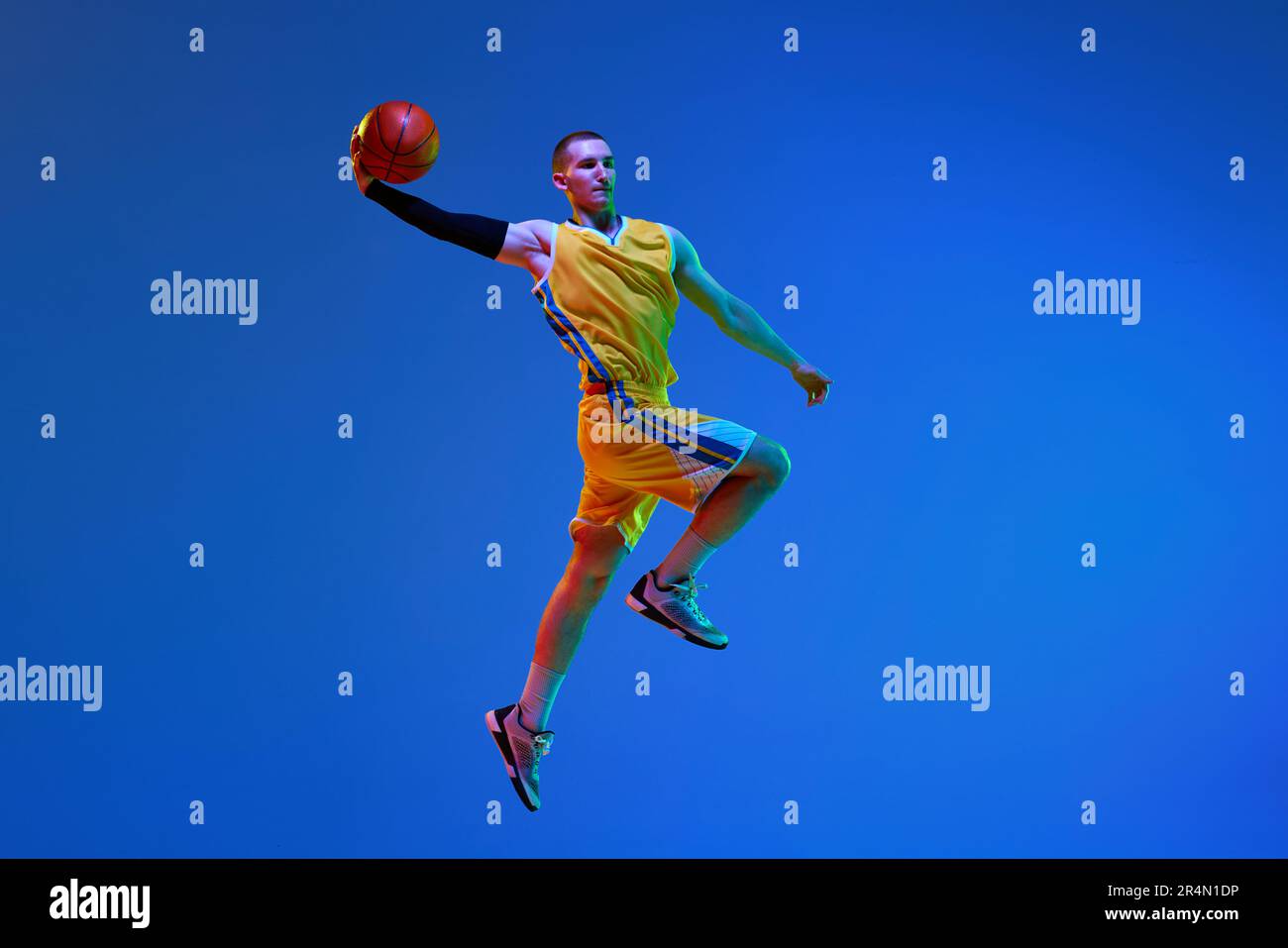 Muscular young man in yellow uniform, basketball player during game ...
