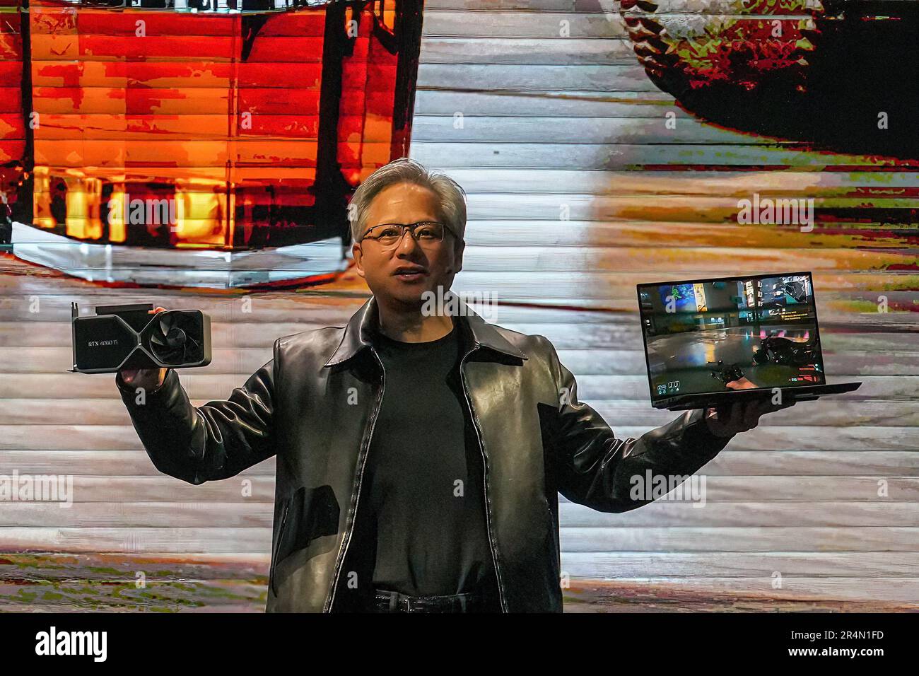 Nvidia president and CEO Jensen Huang holds a graphics card NVIDIA 4060Ti and a laptop at a ...