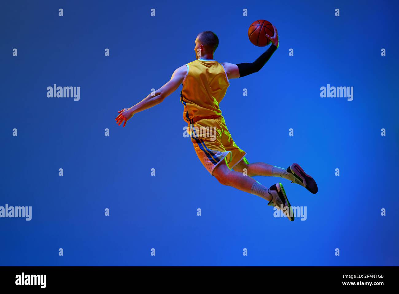 Back view image of young male basketball player in yellow uniform ...
