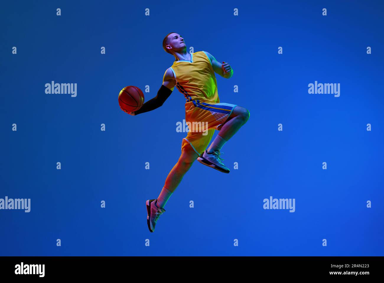 Young man, basketball player in yellow uniform training, throwing ball ...