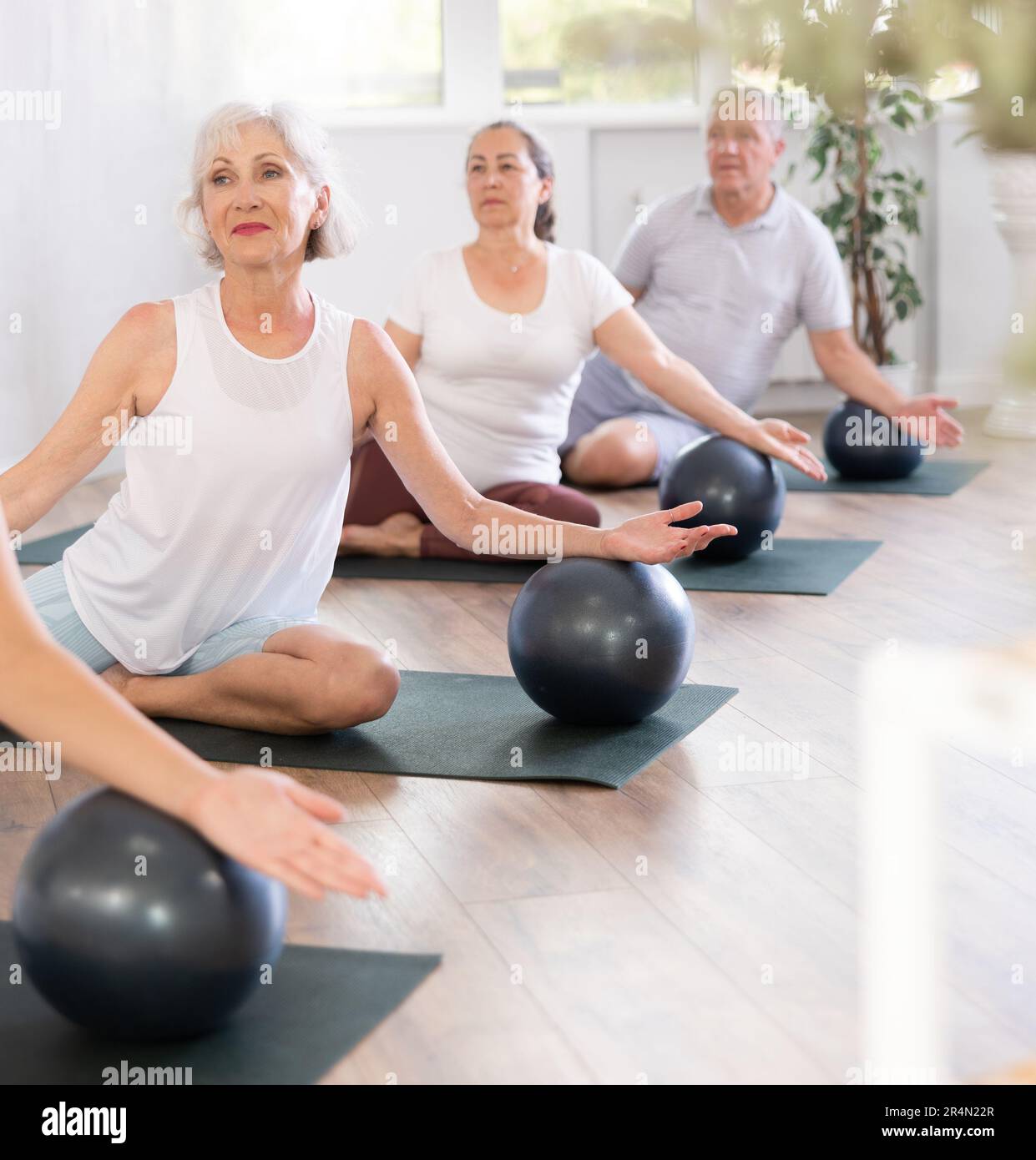 Group of elderly people doing pilates with soft ball in studio Stock ...