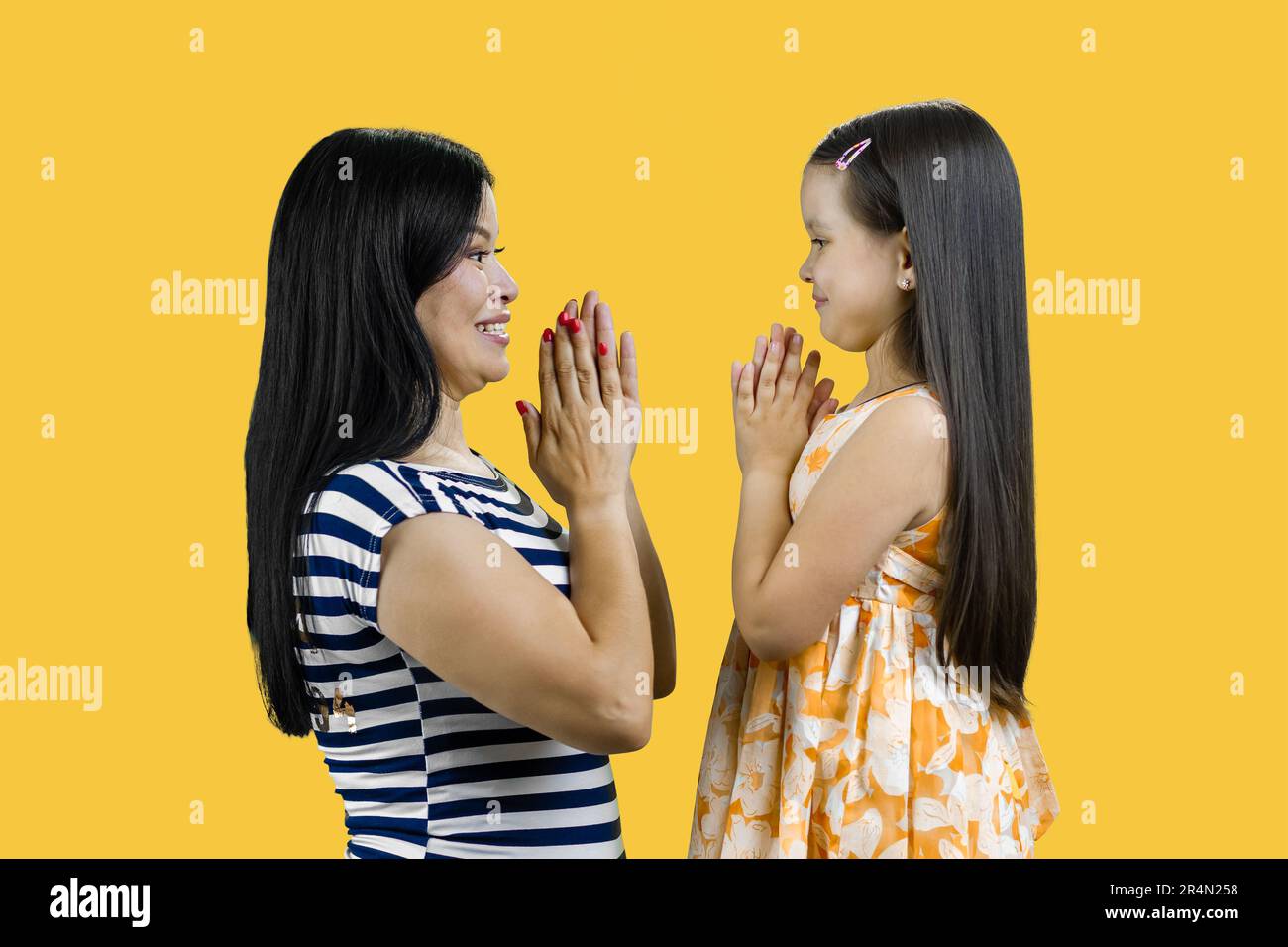 Side view of a young mother and her daughter are playing clapping game ...