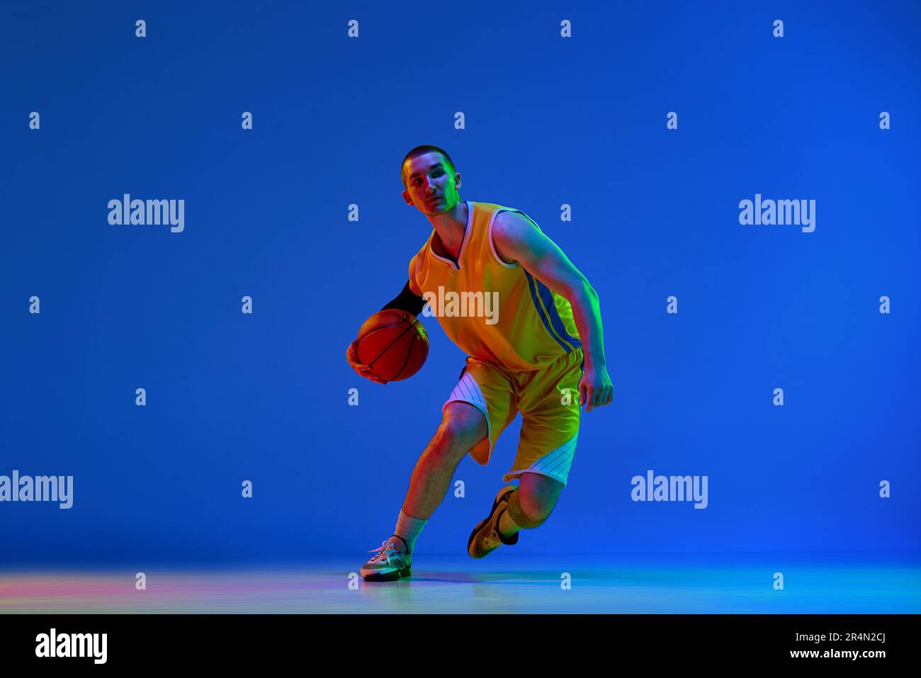 Male basketball player in yellow uniform during game, dribbling ball ...