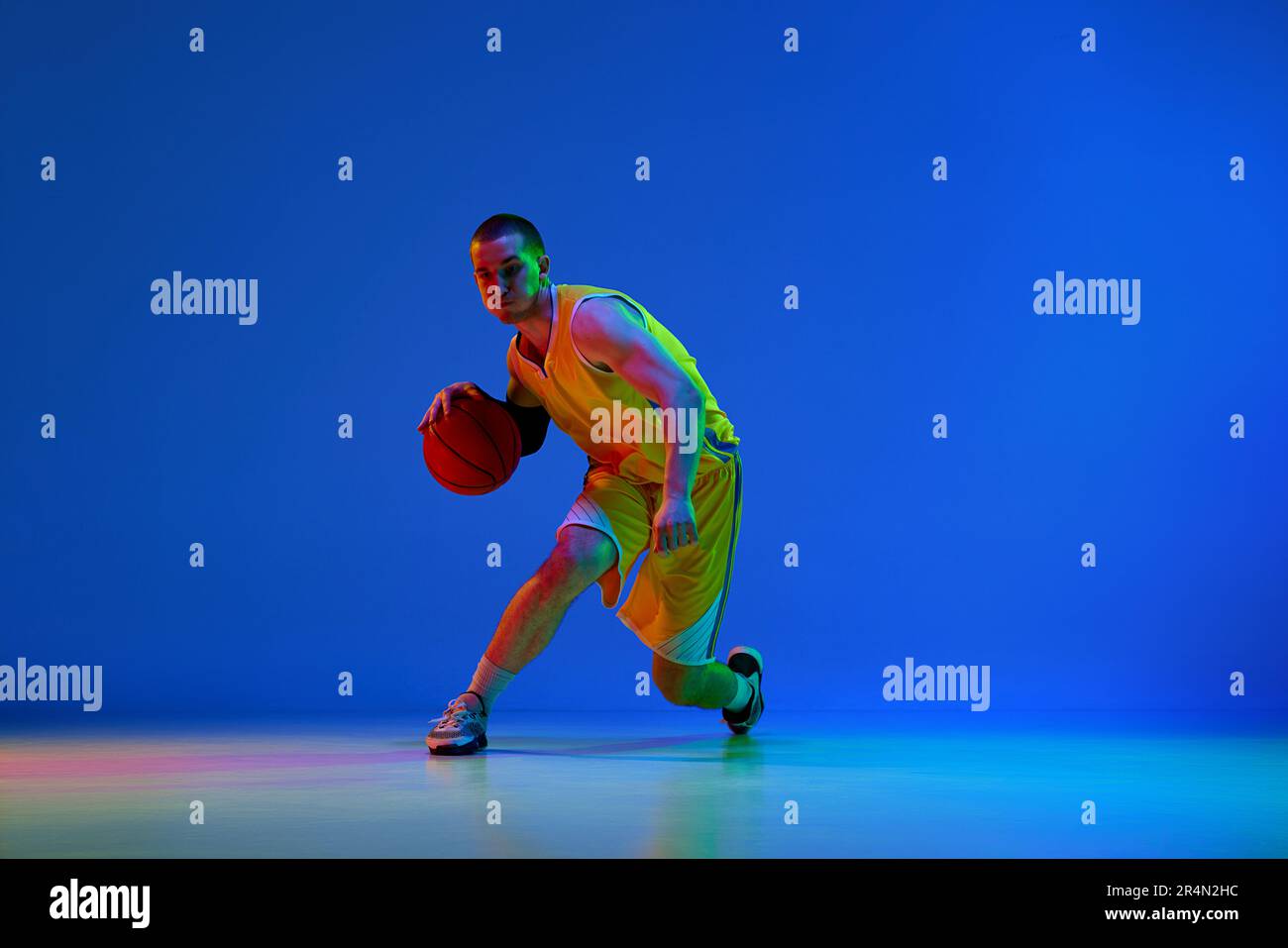 Young man, basketball player in yellow uniform during game, dribbling ...