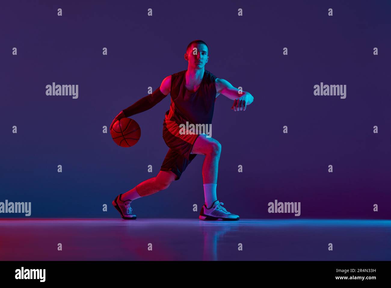 Young sportive man, basketball player in uniform during game, dribbling ...